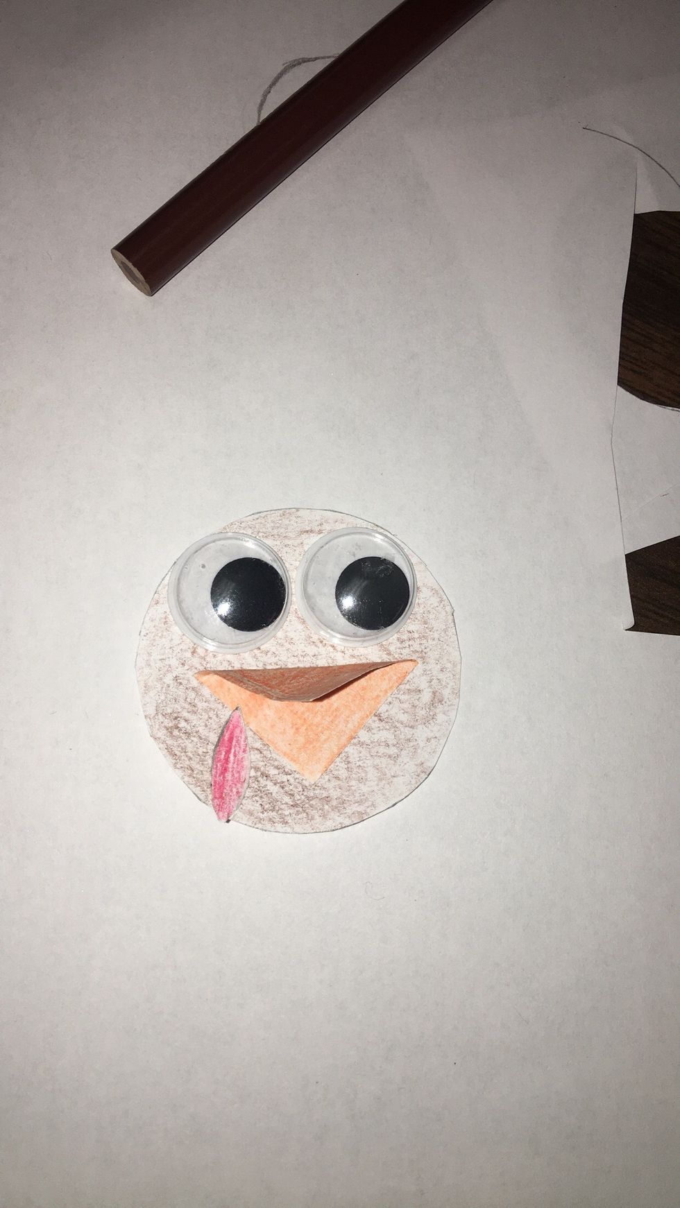 Then, glue the googly eyes, beak, and snood to the head of the turkey ...